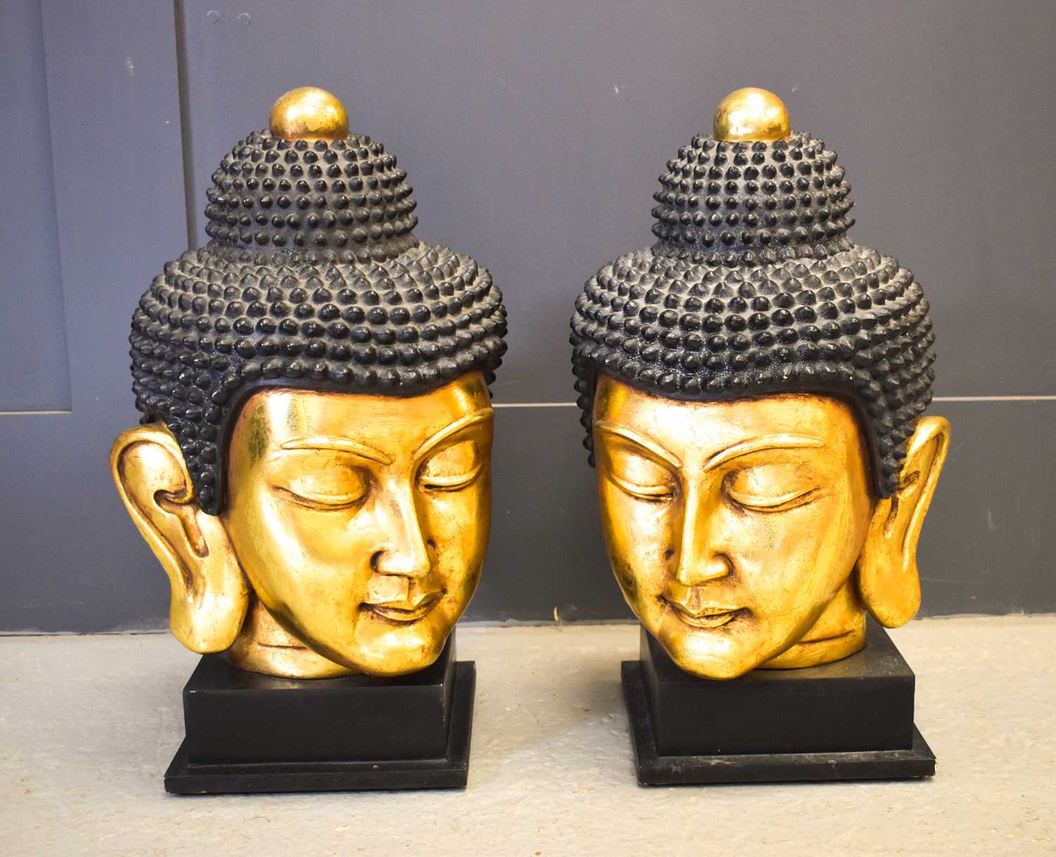 Lot 477 - A pair of 20th century Buddha heads, with